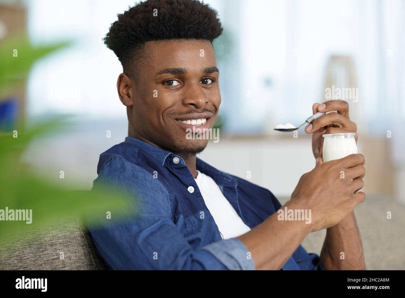portrait of young man eating yogurt Stock Photo - Alamy