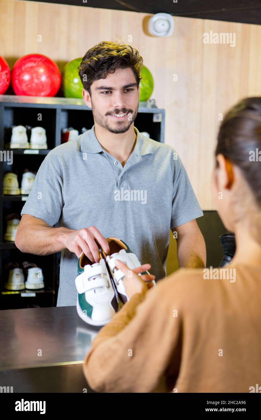 worker giving shoes to customer for bowling Stock Photo - Alamy