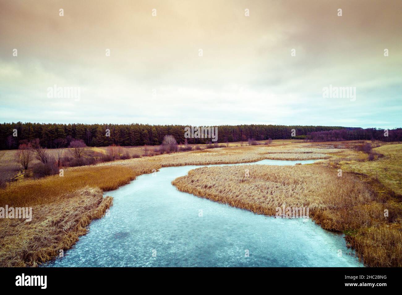 Aerial view of the countryside and frozen winding brook in the evening ...