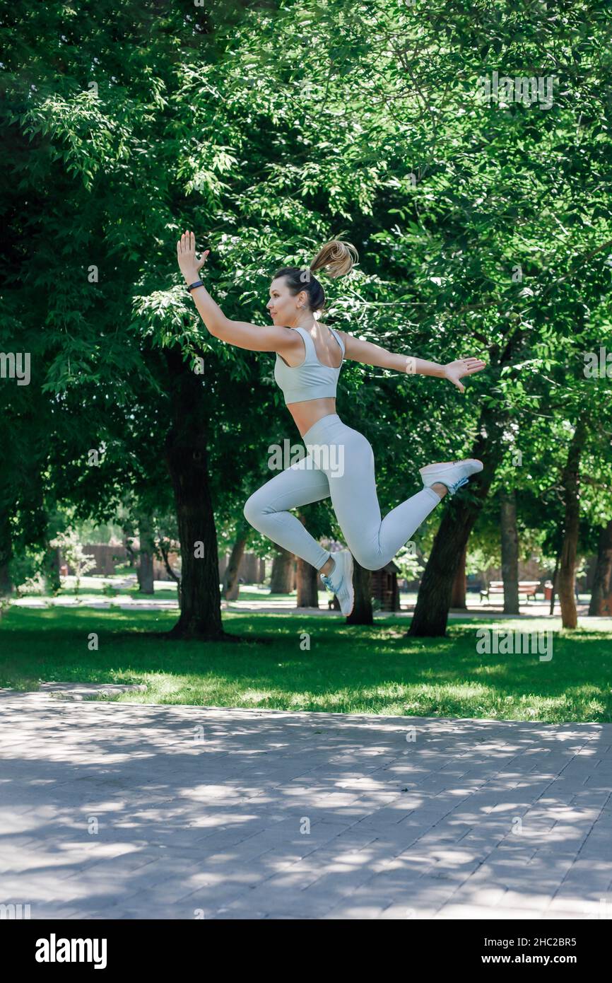 beautiful young sporty woman jumping in air stretching out arms ...