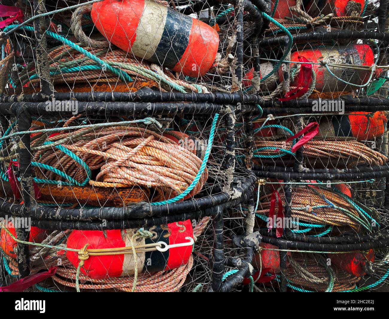 Lobster traps and crab traps with buoys stacked by the shore in a ...