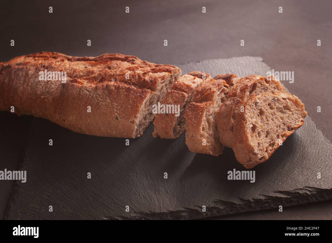 Fresh crispy French baguette on a black stone background. Wrapping ...