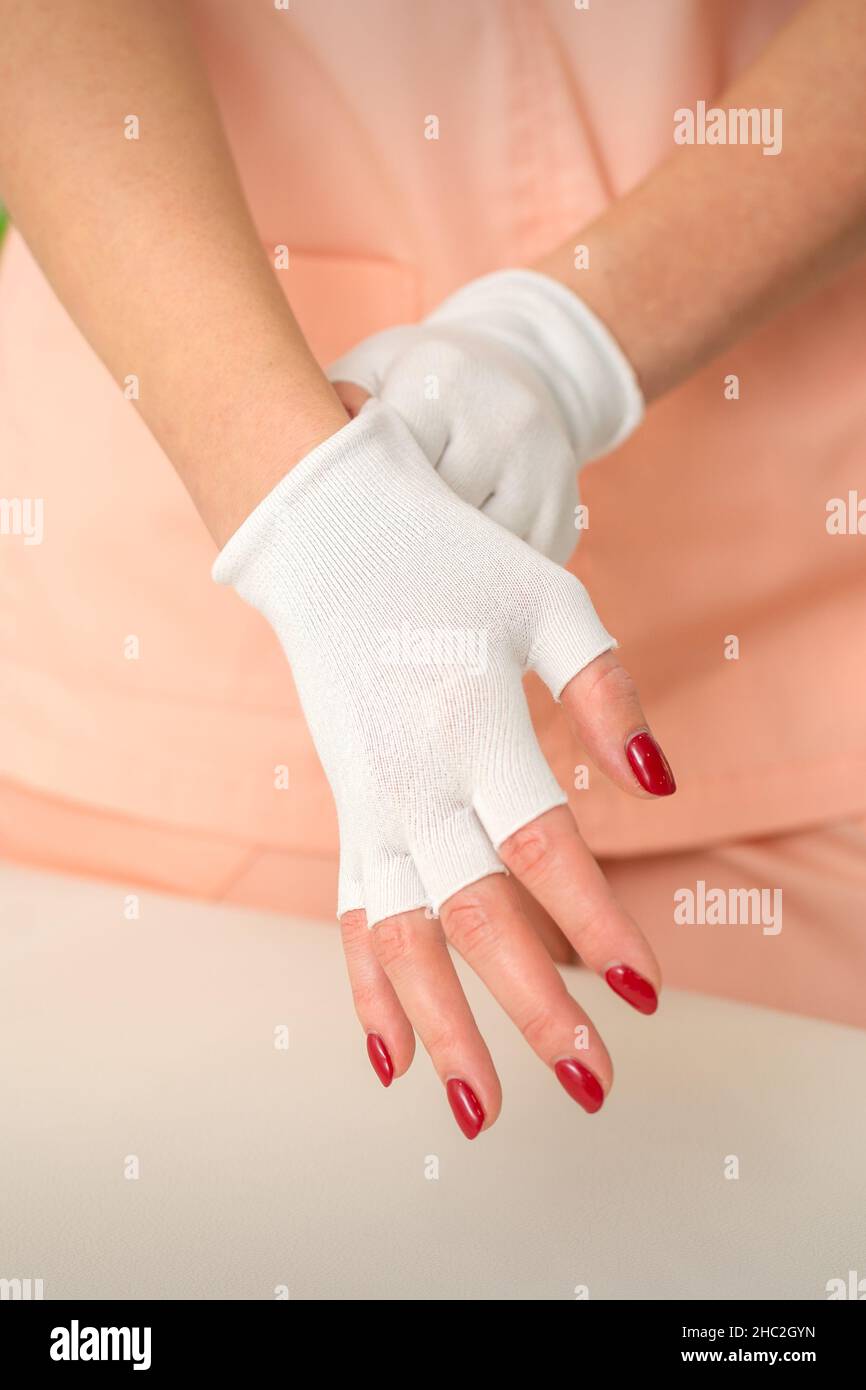 Cosmetician in workwear wearing white bamboo fingerless gloves on her ...