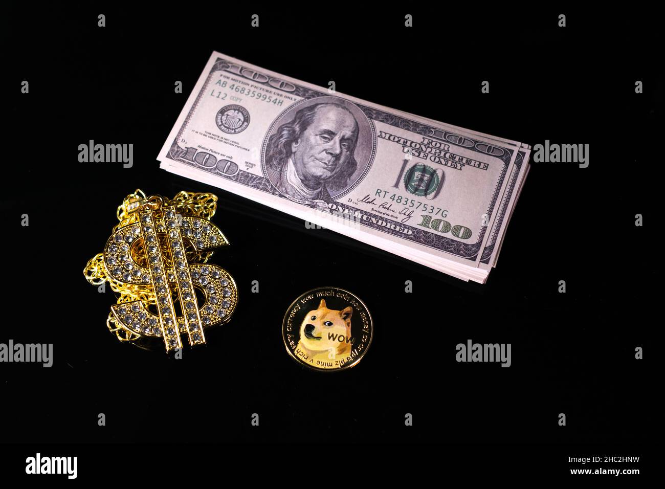 one dogecoin coin lies next to a stack of $100 bills and a diamond ...
