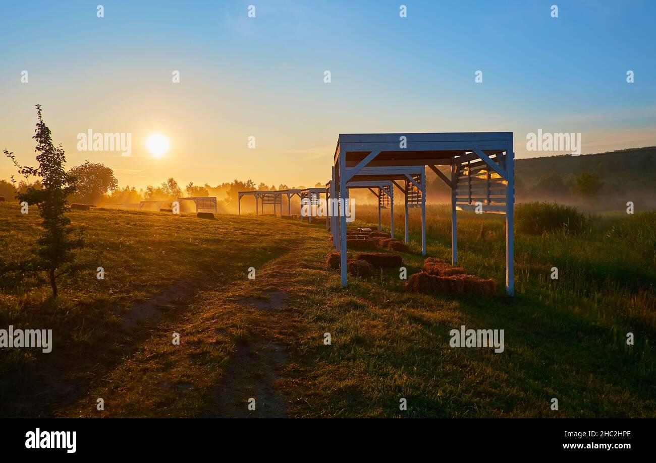 The wooden pavilions at the foot of the hilly meadow against the ...