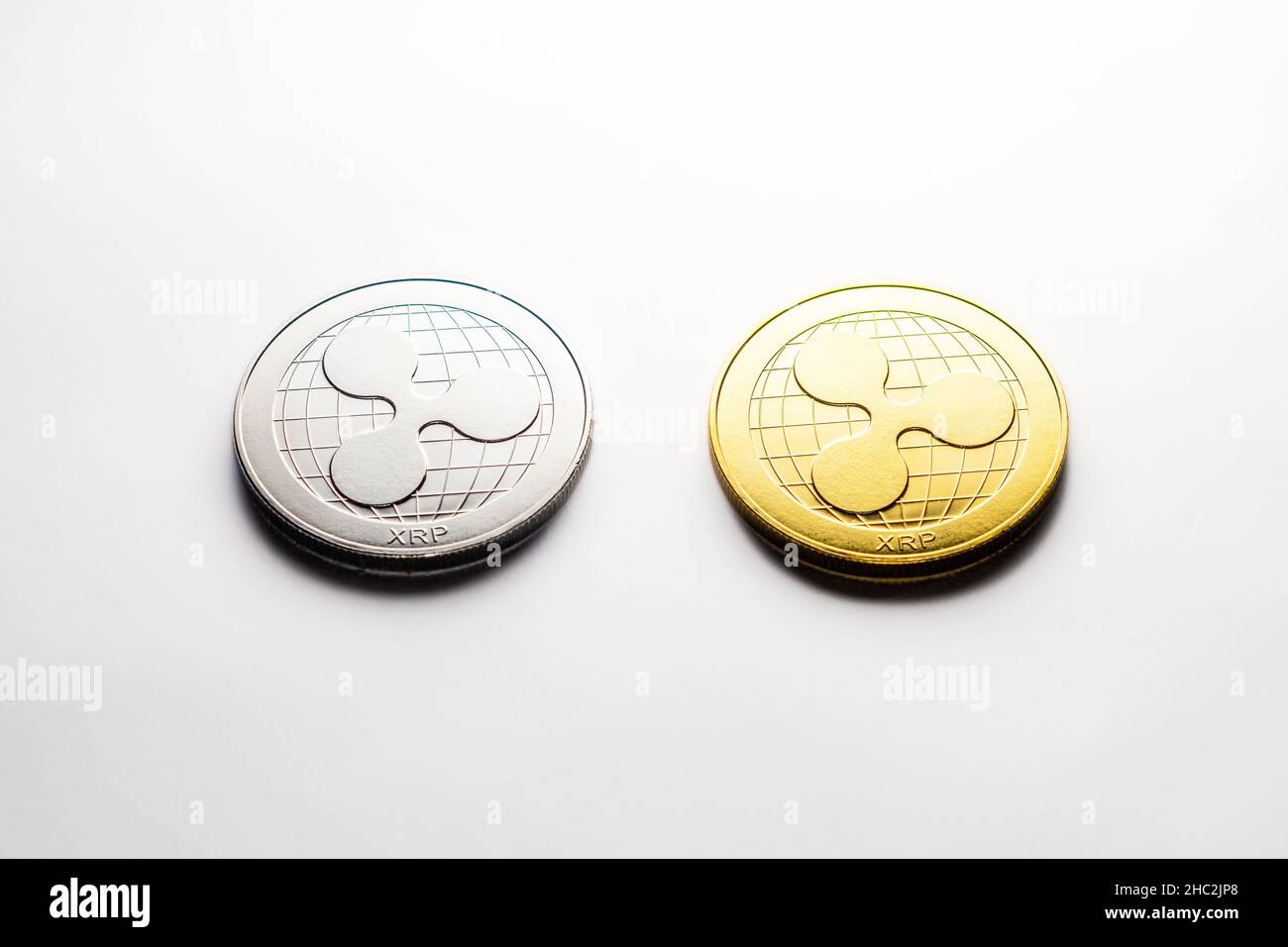 Multiple XRP-Ripple silver and gold coins photographed on a white ...