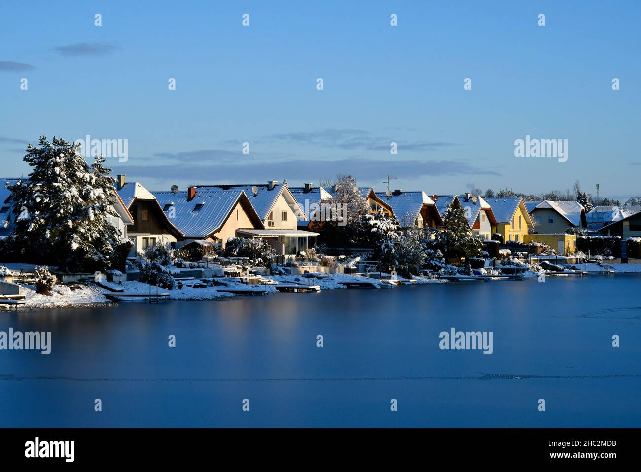 Austria, houses in a residential estate on a small frozen lake covered ...