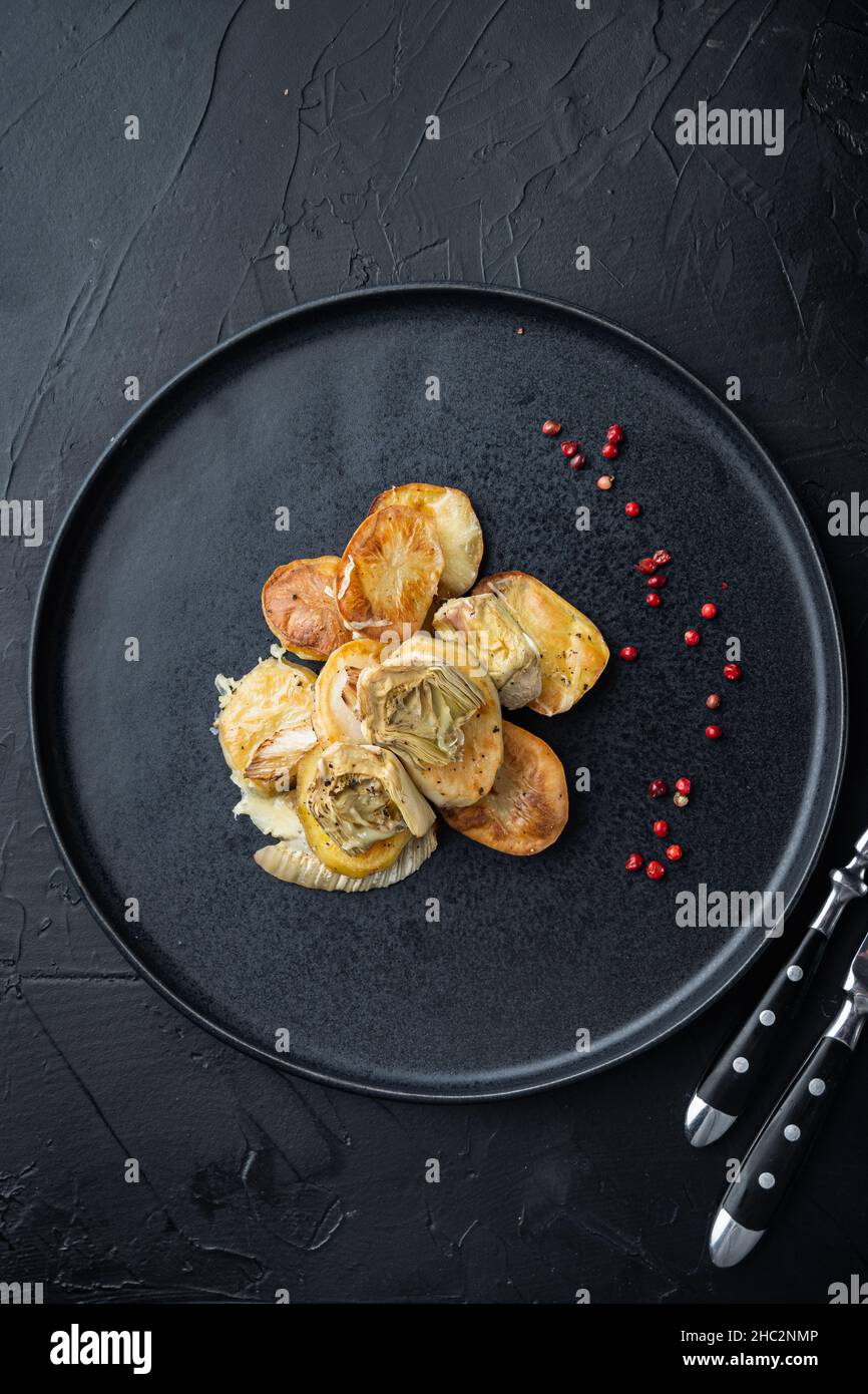Baked potato, artichoke with fennel al forno, on black textured ...