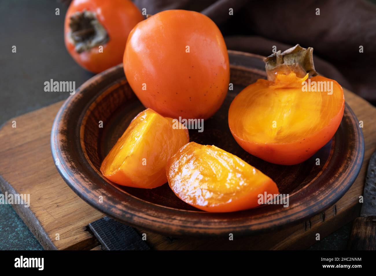 Fresh organic ripe Persimmons fruits in wooden bowl with slice on a ...