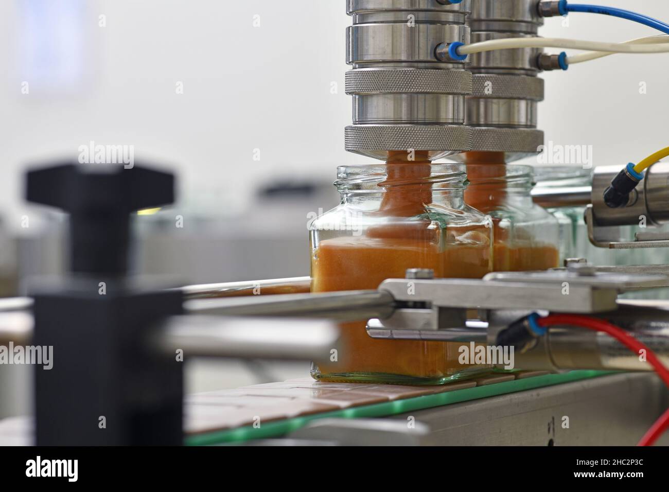 Jars of creamed honey in a packaging line at a commercial honey factory ...