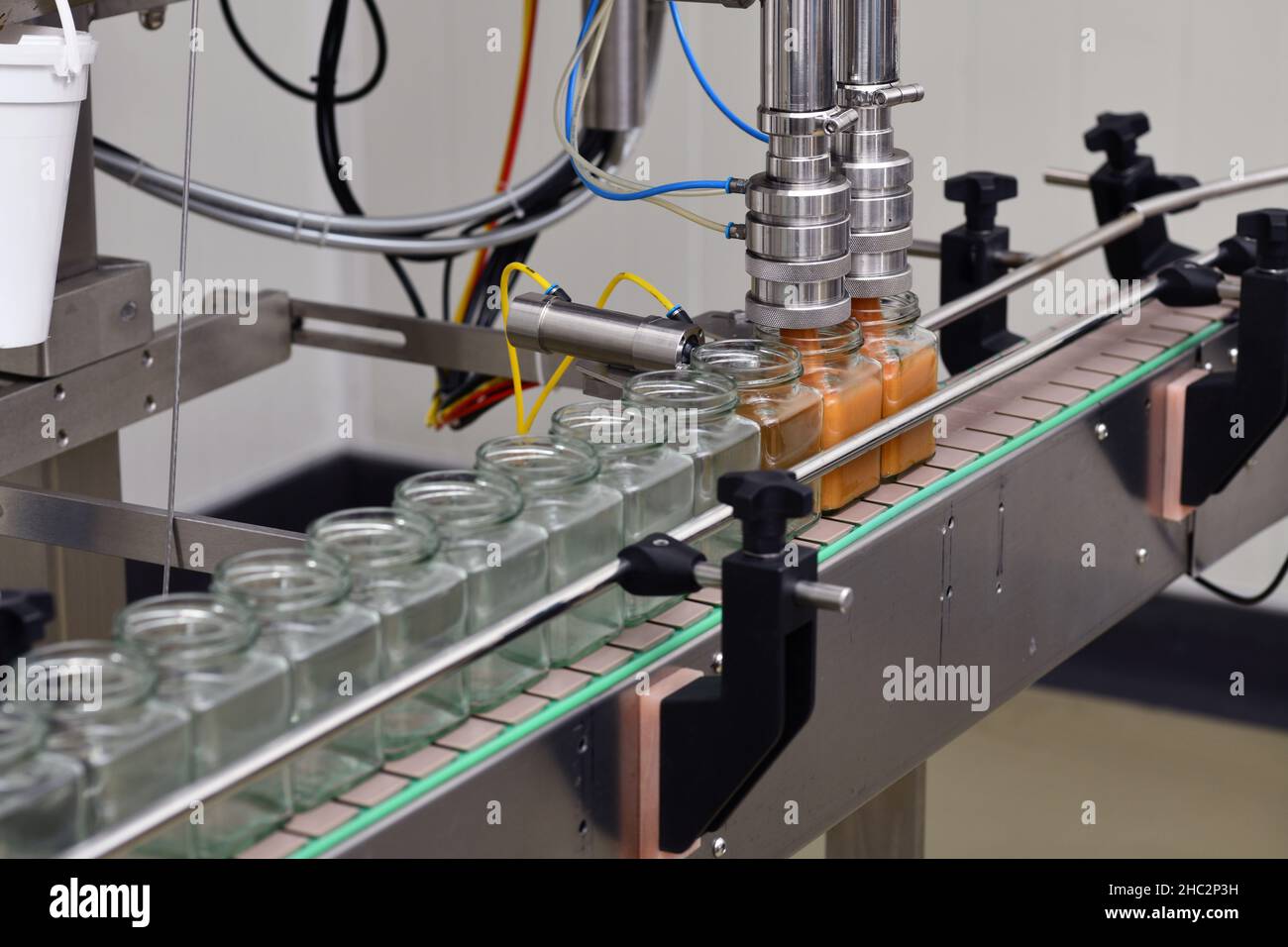 Jars of creamed honey in a packaging line at a commercial honey factory ...