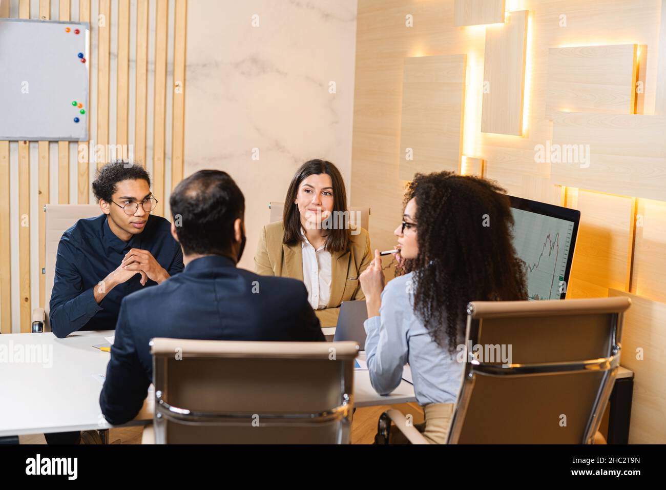 Working hard to win. Four young colleagues discussing documents for a ...