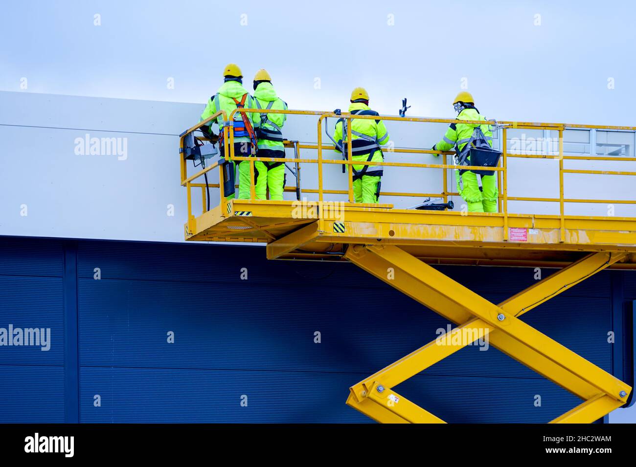 yellow self propelled scissor lift with workers in uniform and safety ...