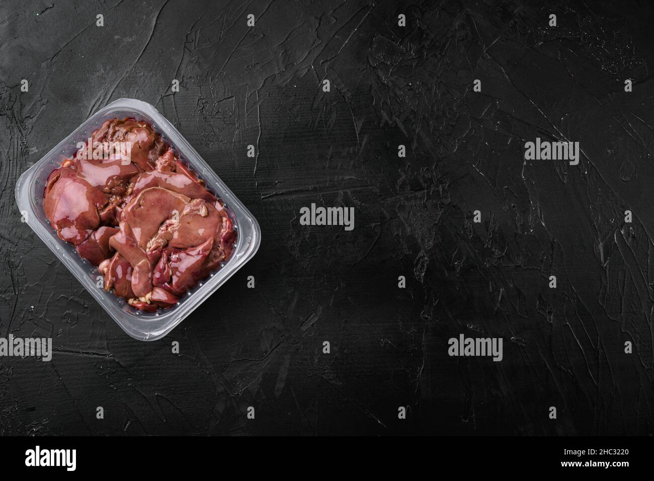 Poultry offal Chicken liver in a plastic container set, on black dark ...