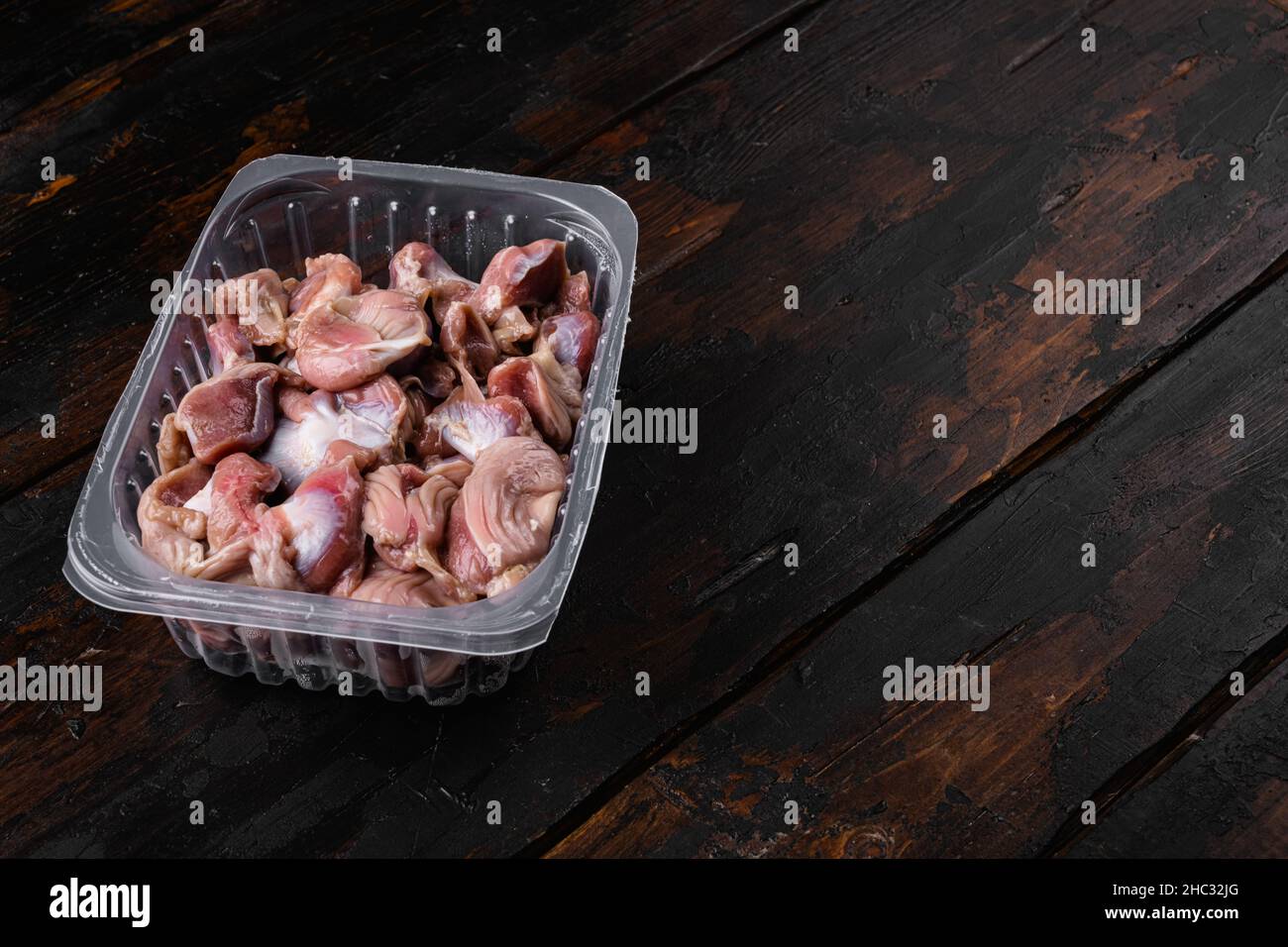 Raw uncooked chicken gizzards, stomach in plastic pack set, on old dark ...