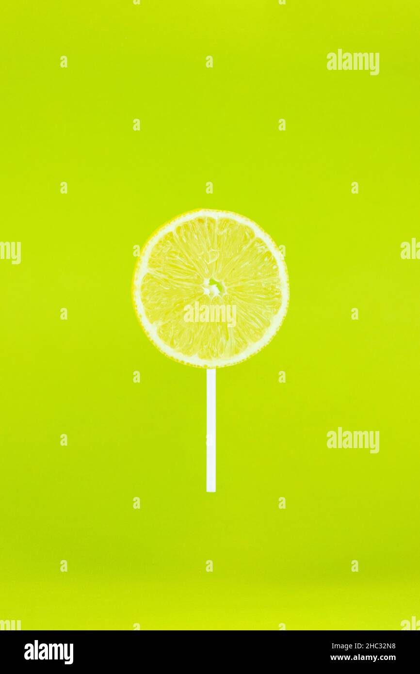 Lemon lollipop with stick on light green background. Candy food minimal ...