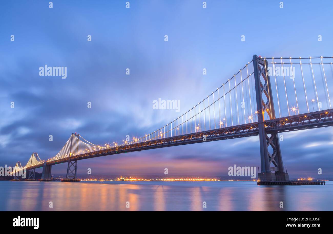 A photograph captures the iconic Bay Bridge in San Francisco, bathed in ...