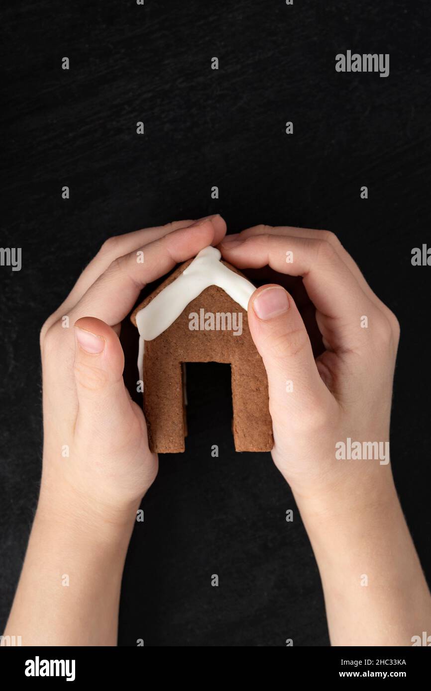 Child hands holding gingerbread house. Top view, black background Stock ...