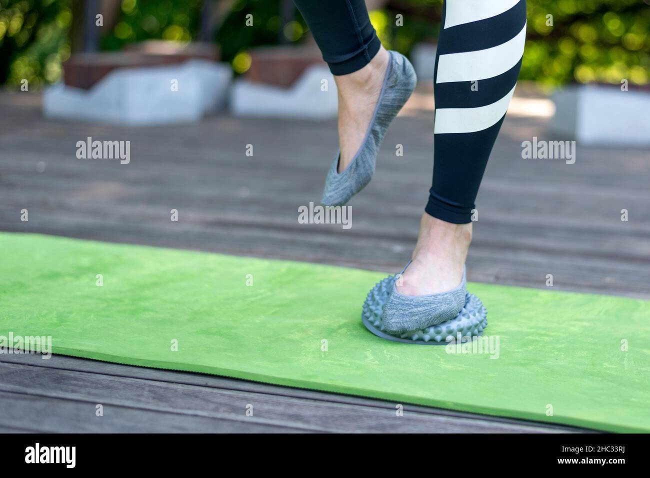 Girl stands with one foot on balancing disc with spikes. Impact on the ...