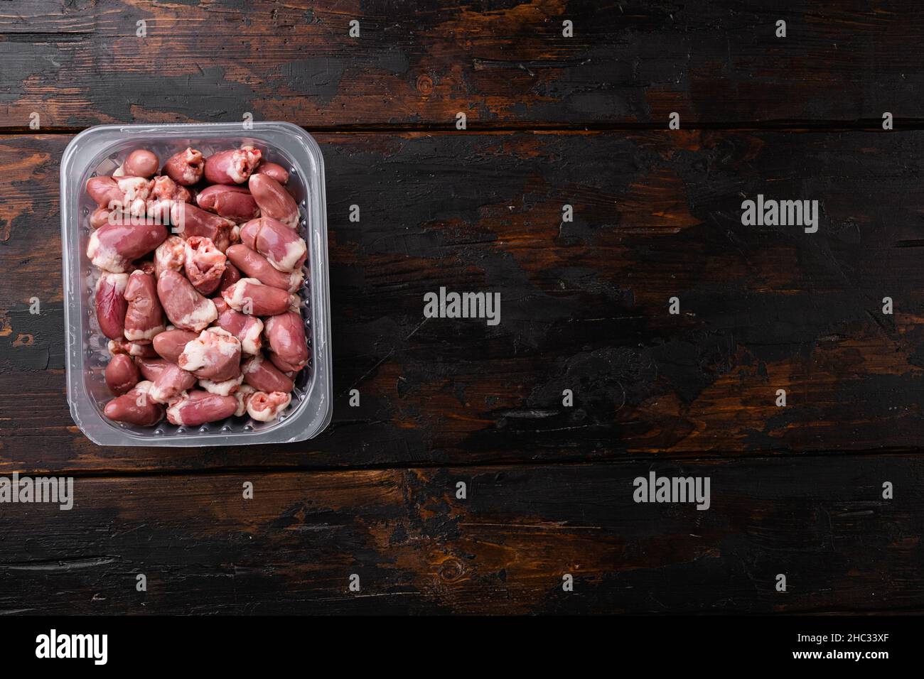 Raw turkey hearts in plastic pack set, on old dark wooden table ...