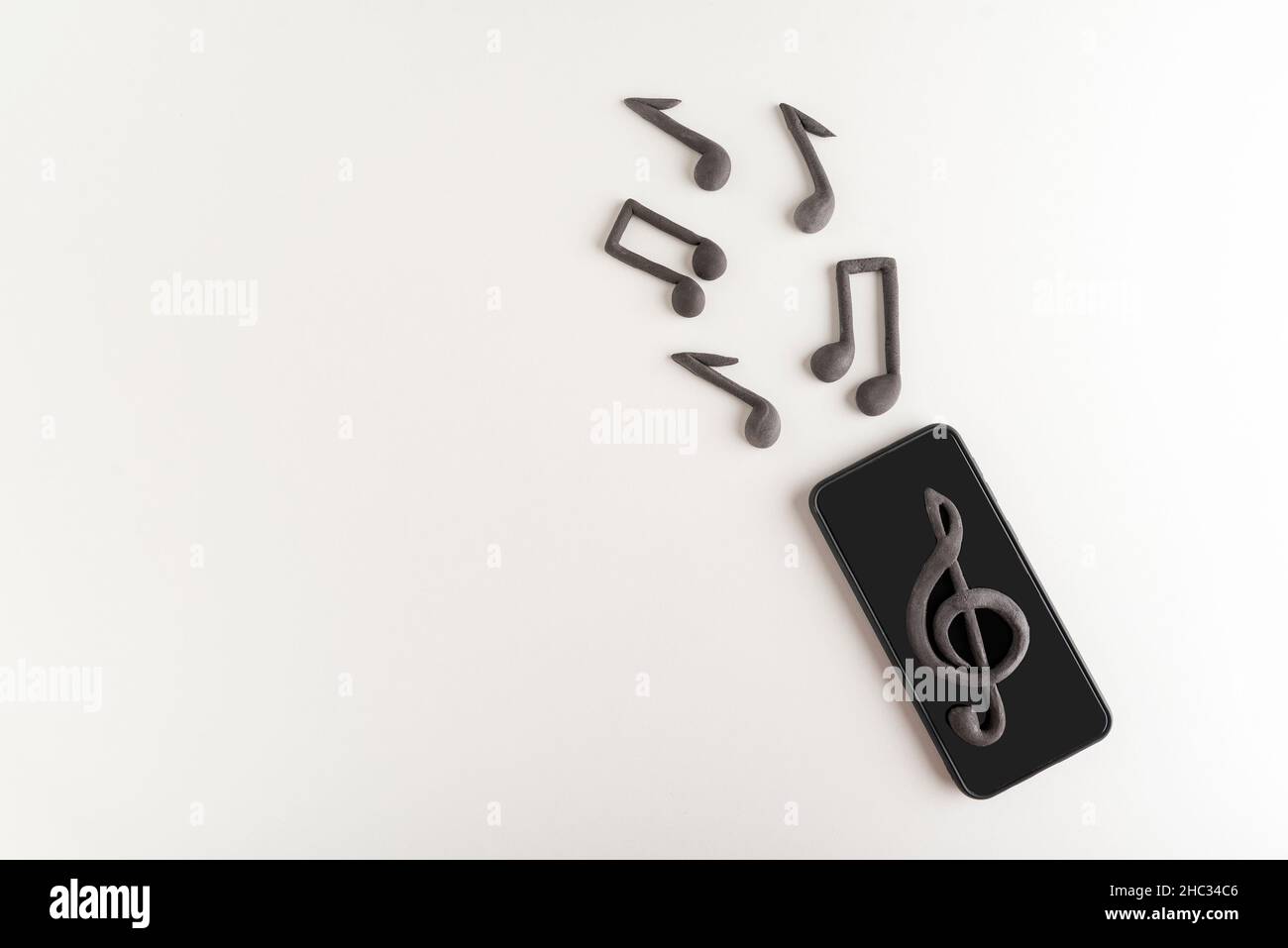 Mobile phone with treble clef on display and musical notes on white ...