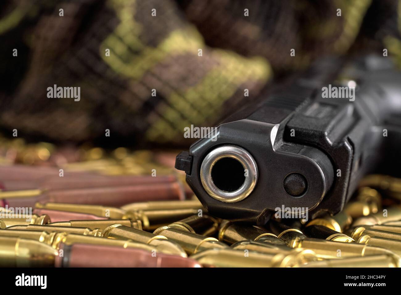 Yellow brass and brown bronze bullets, with black gun barrel near ...