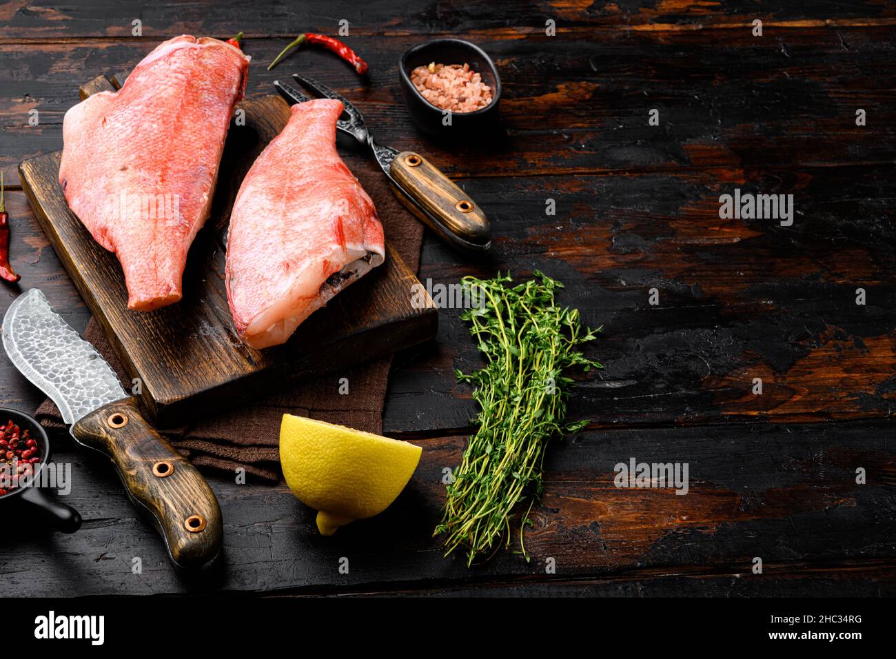 Raw red sea bass fish set, on wooden cutting board, on old dark wooden ...