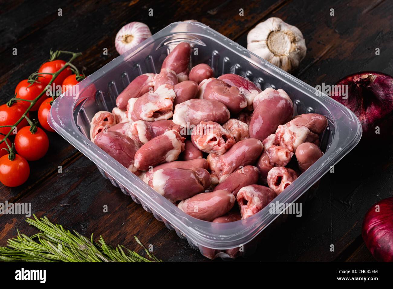 Raw turkey hearts in plastic pack set, on old dark wooden table ...