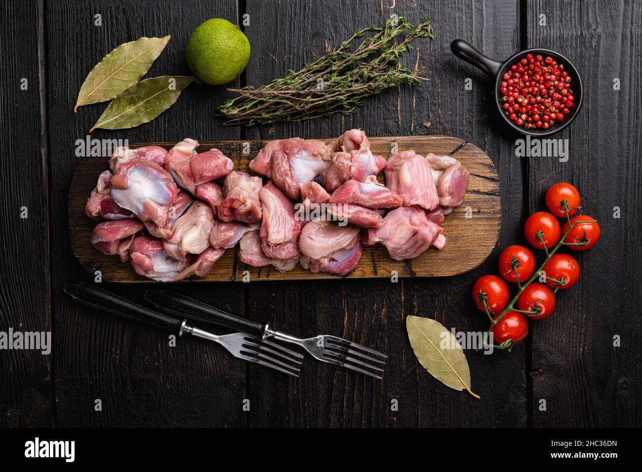 Raw uncooked chicken gizzards, stomach set, on black wooden table ...
