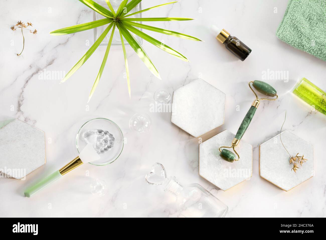 Self made moisturizer and green jade face roller on marble hexagons ...