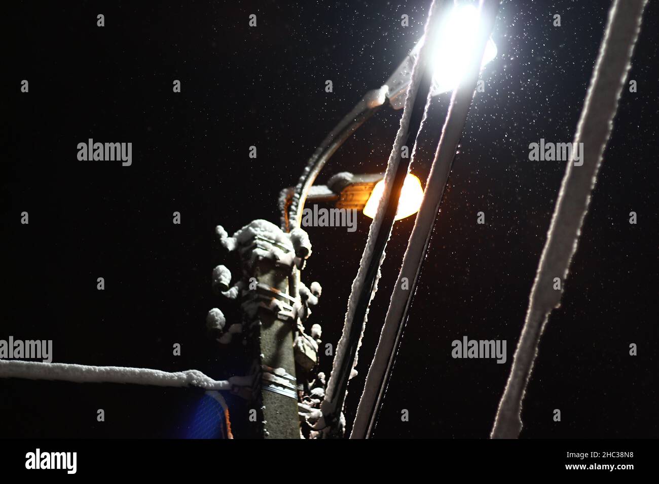 Snowfall and snow on wires under a street lamp at night Stock Photo - Alamy