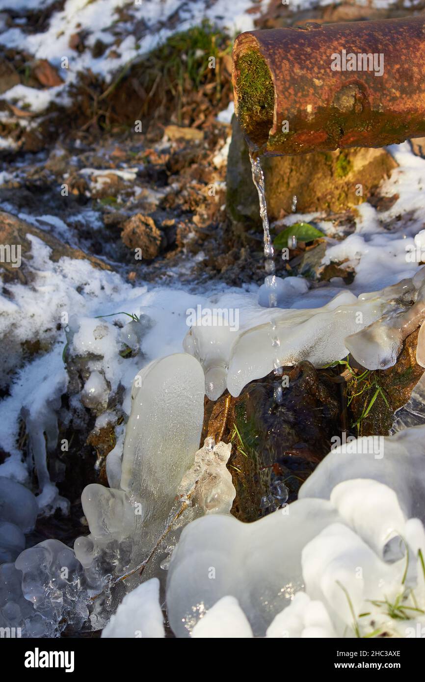 Spring water falling from a pipe in winter Stock Photo - Alamy