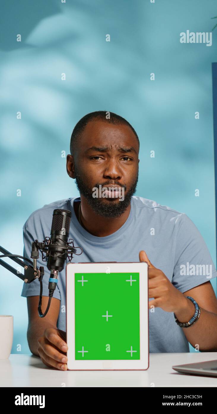 Blogger vertically holding green screen on tablet and filming video for ...