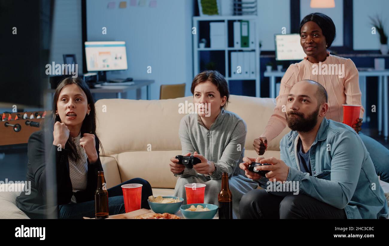 Multi ethnic group of workmates playing video games with controllers ...