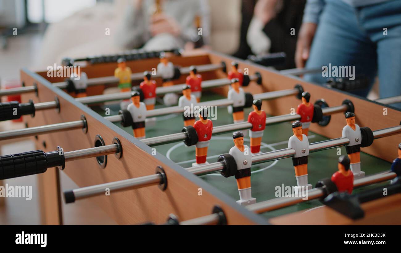 Close up of colleagues playing at foosball table after work. Workmates ...