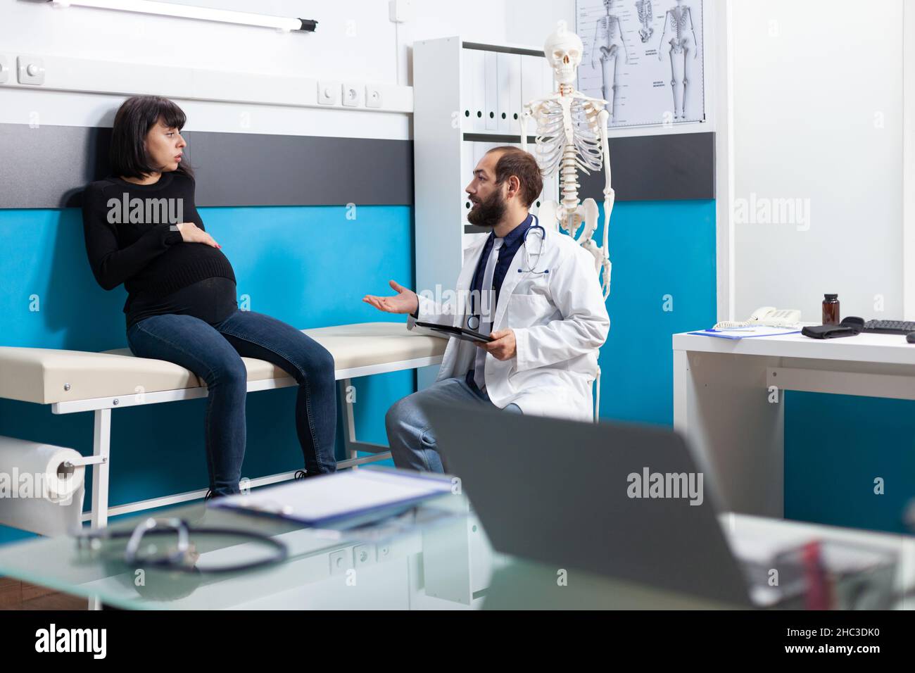General Practitioner Consulting Pregnant Woman In Cabinet Doing