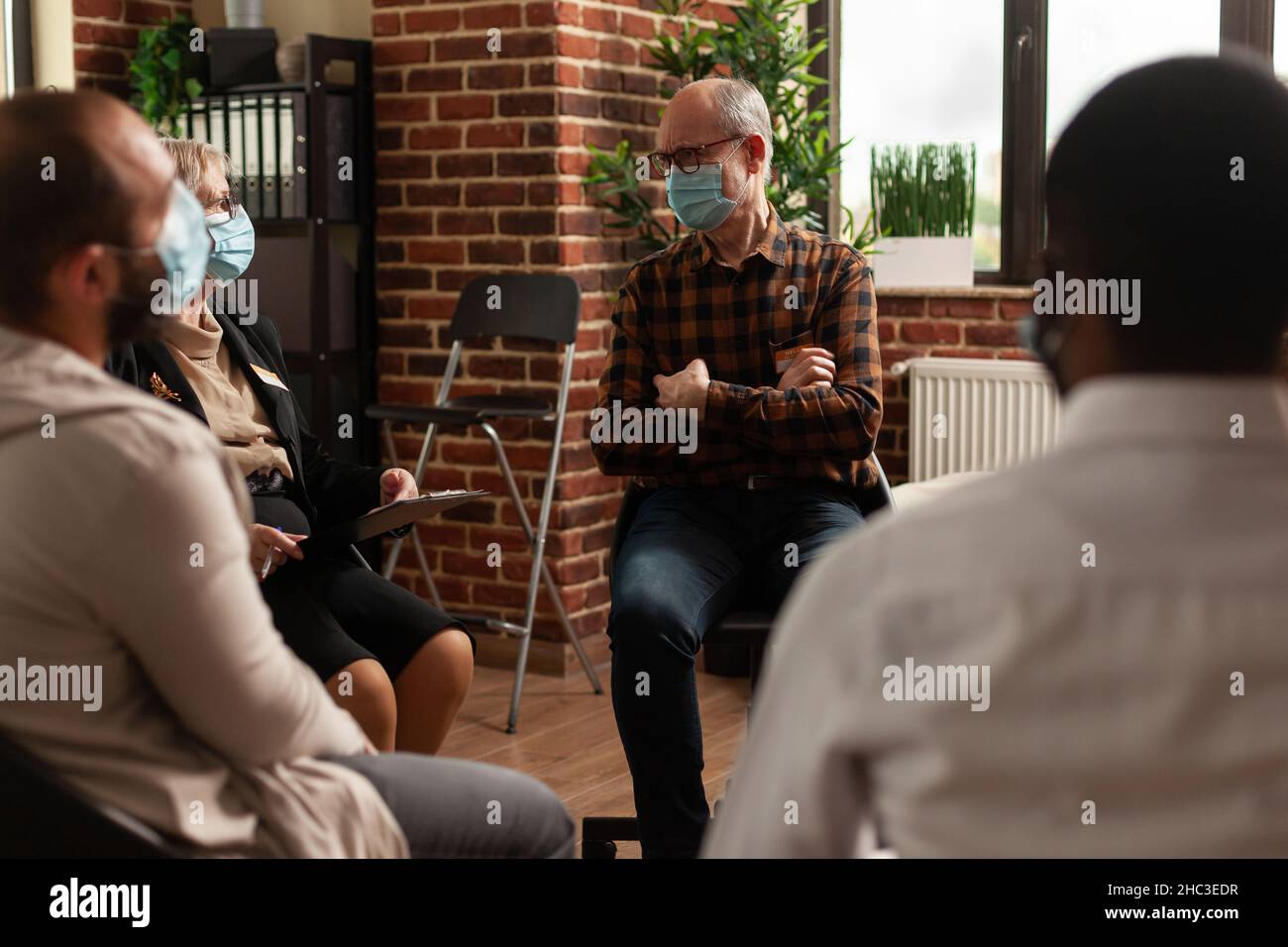 Senior man with face mask talking to people in circle at aa meeting, to ...