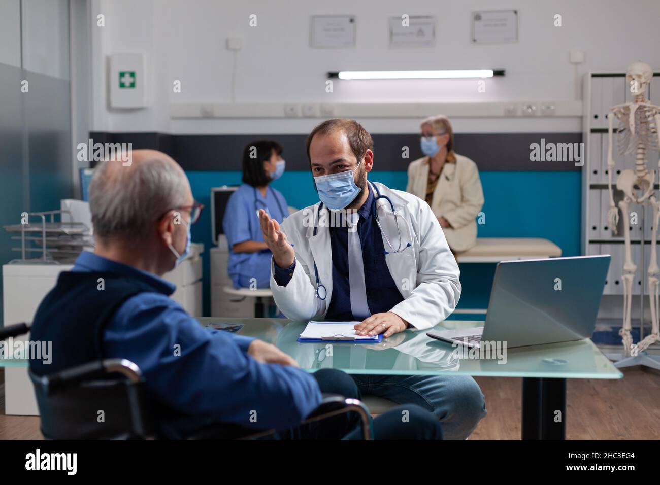 Doctor consulting elder man with physical disability in office, doing ...