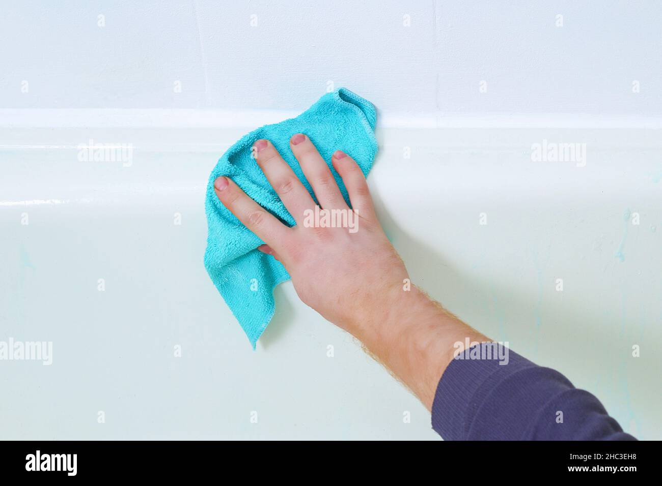 A man applies a bath cleaner and rubs the bath with a brush, rag ...