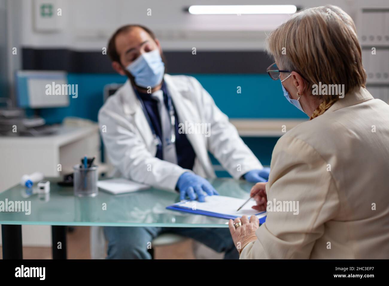 Senior patient signing checkup papers to receive prescription medicine ...