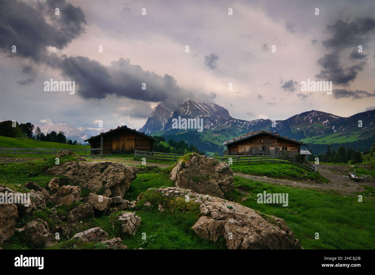 Landscape of old wooden barns surrounded by rocky hills in the evening ...