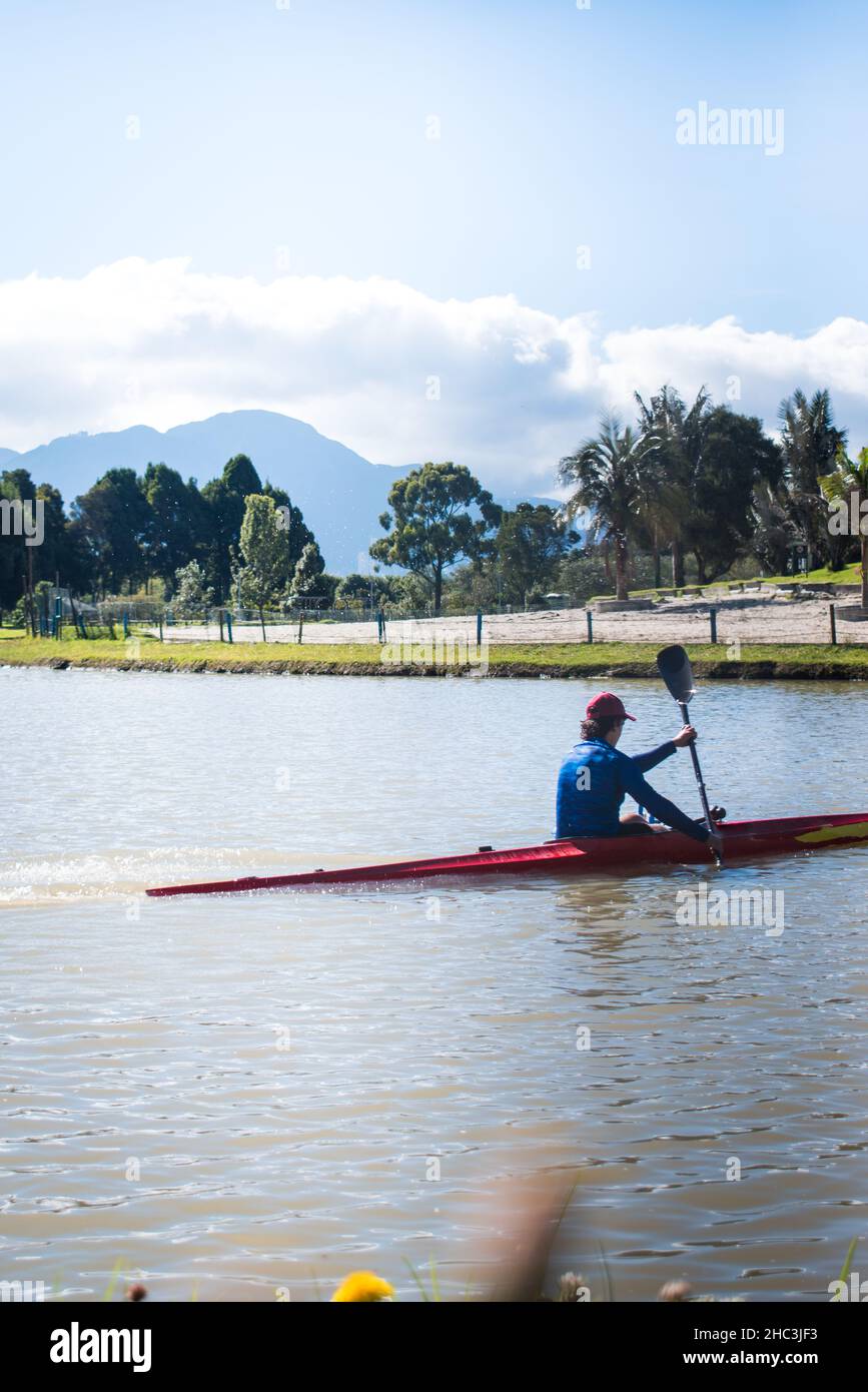Man practicing rowing in a lake with mountains and trees at background ...
