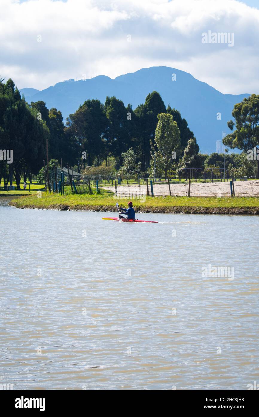 Man practicing rowing in a lake with mountains and trees at background ...