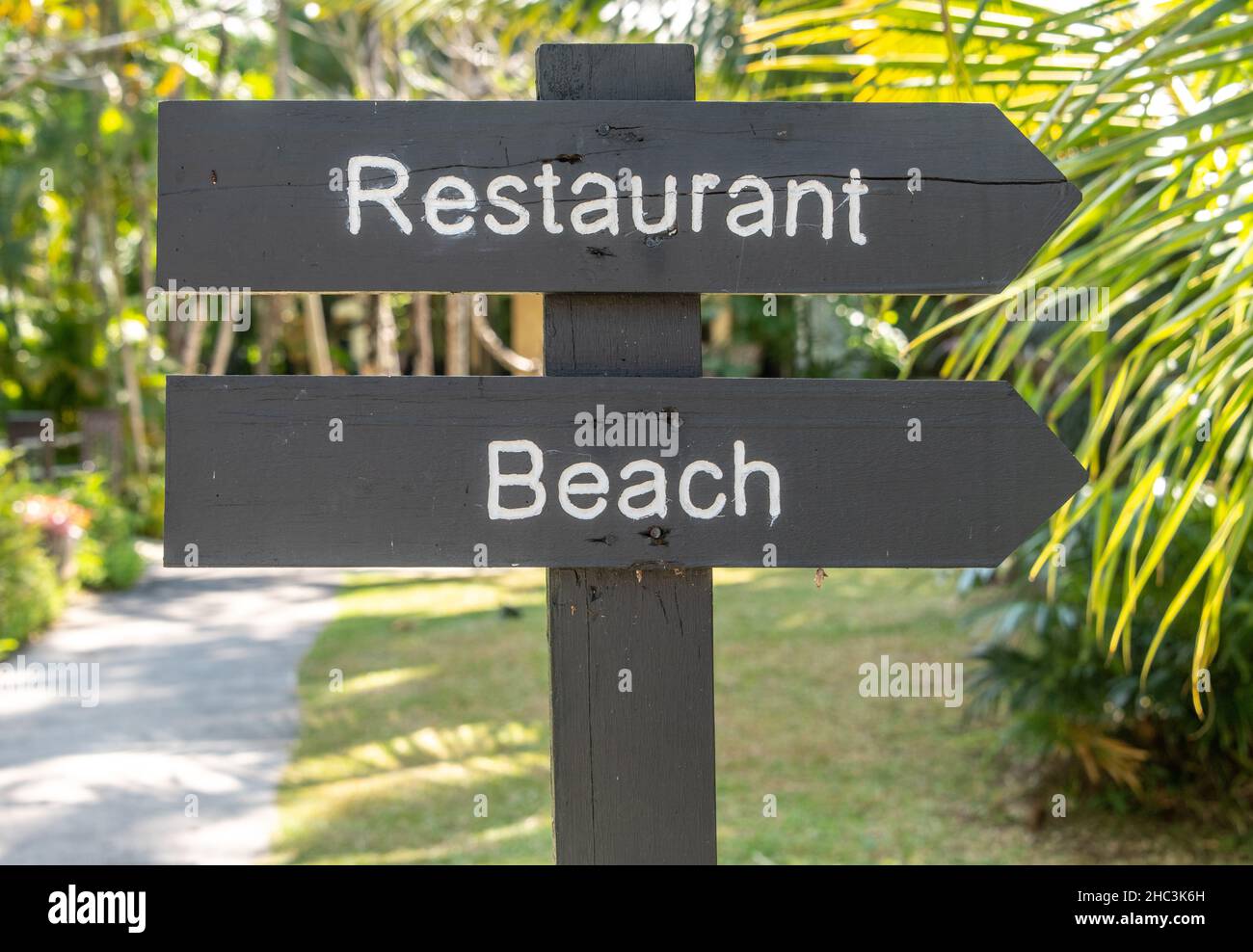Wooden sign pointing to restaurant and beach Stock Photo - Alamy