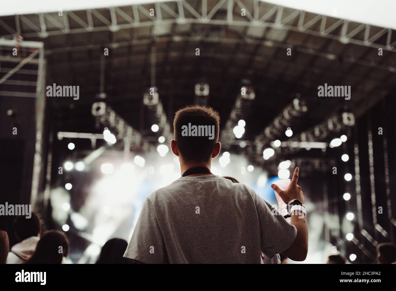 Back view of a young man enjoying a concert against smoky stage ...
