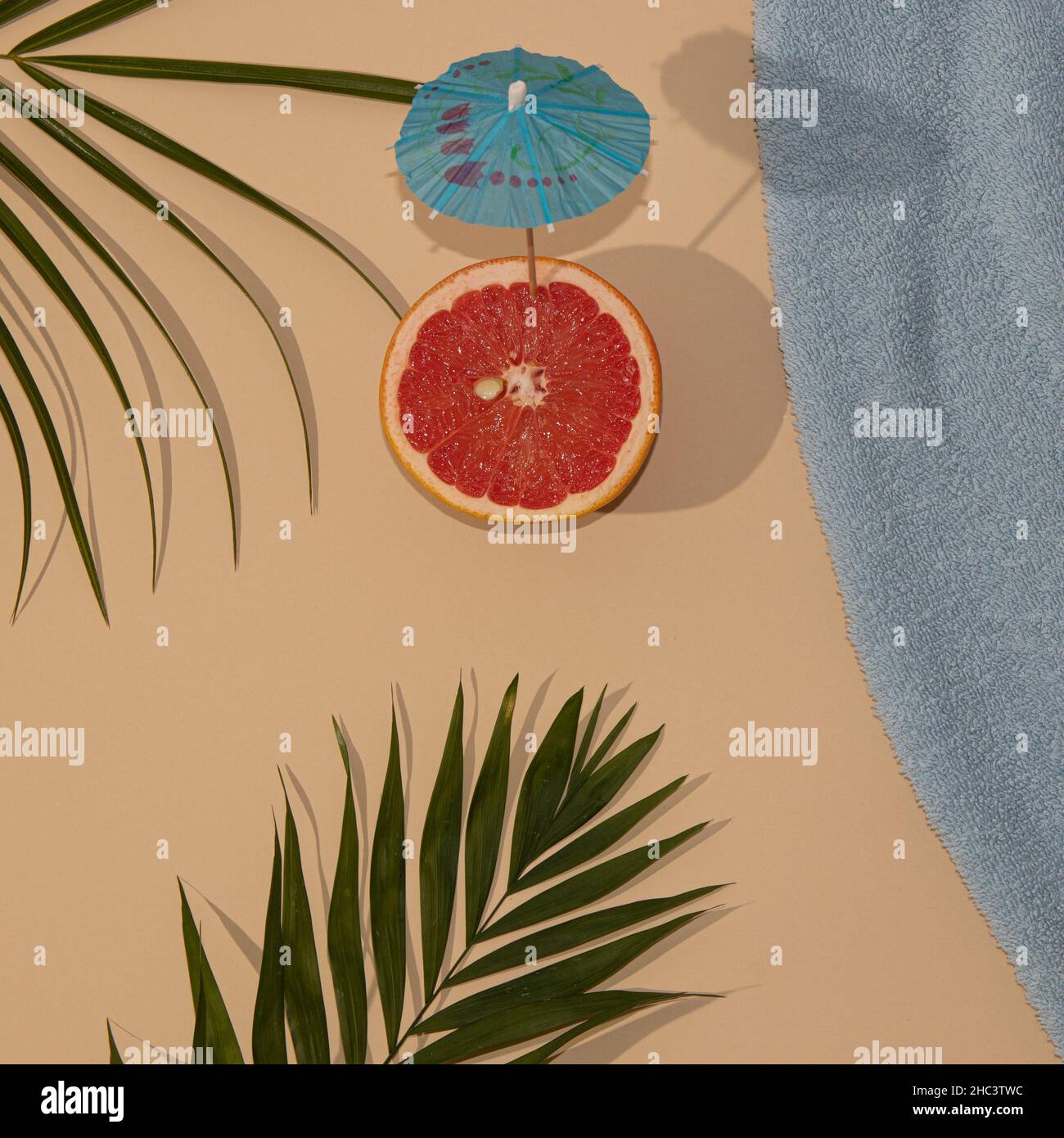 Summer scene with blue beach towel and palm leaves and grape with ...