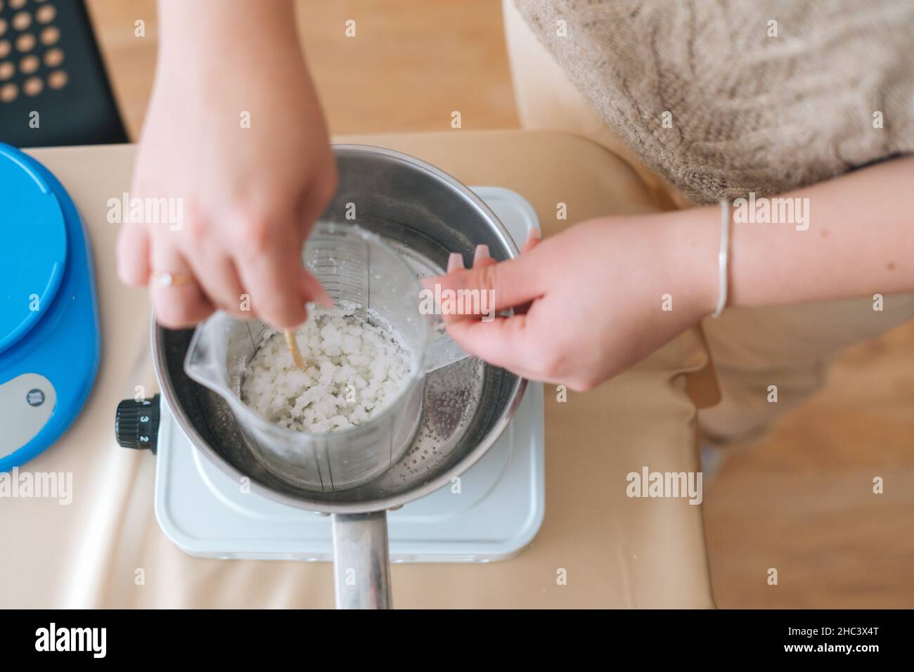 High-angle view of female artisan mixing ingredients for hand candle ...