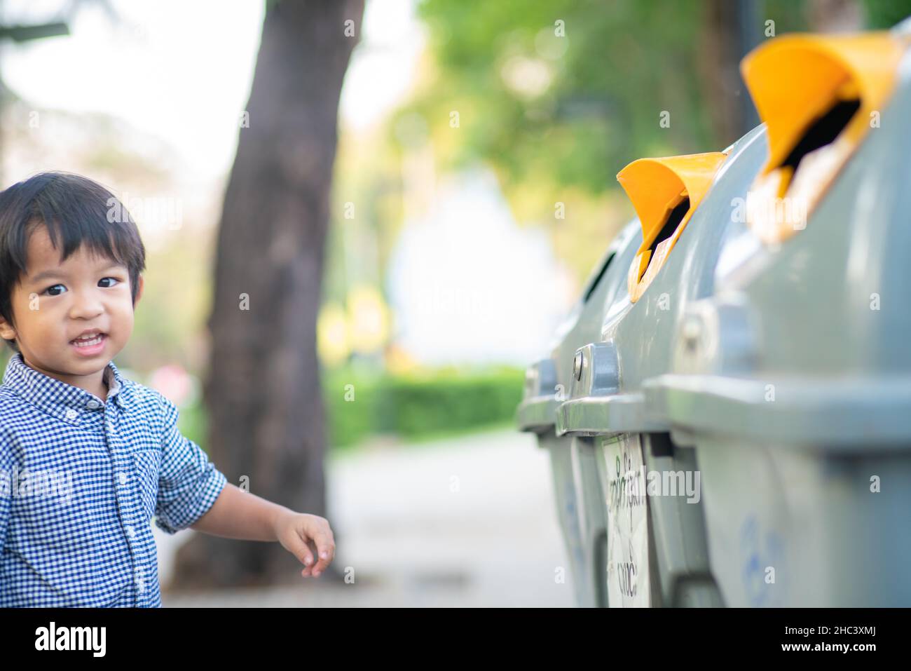 Adorable little boy keep garbage clean to bin in park eco environmennt ...