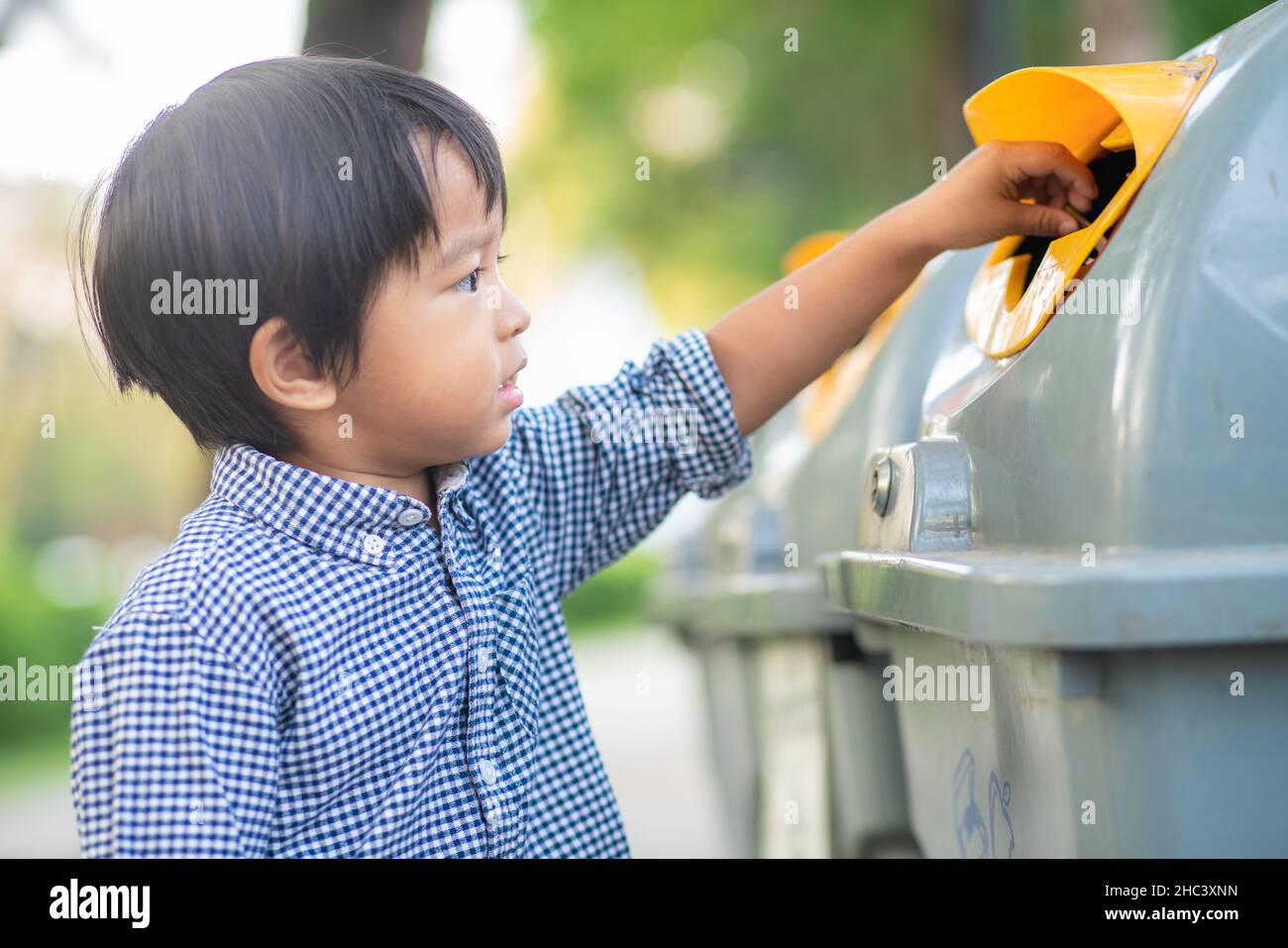 Adorable little boy keep garbage clean to bin in park eco environmennt ...