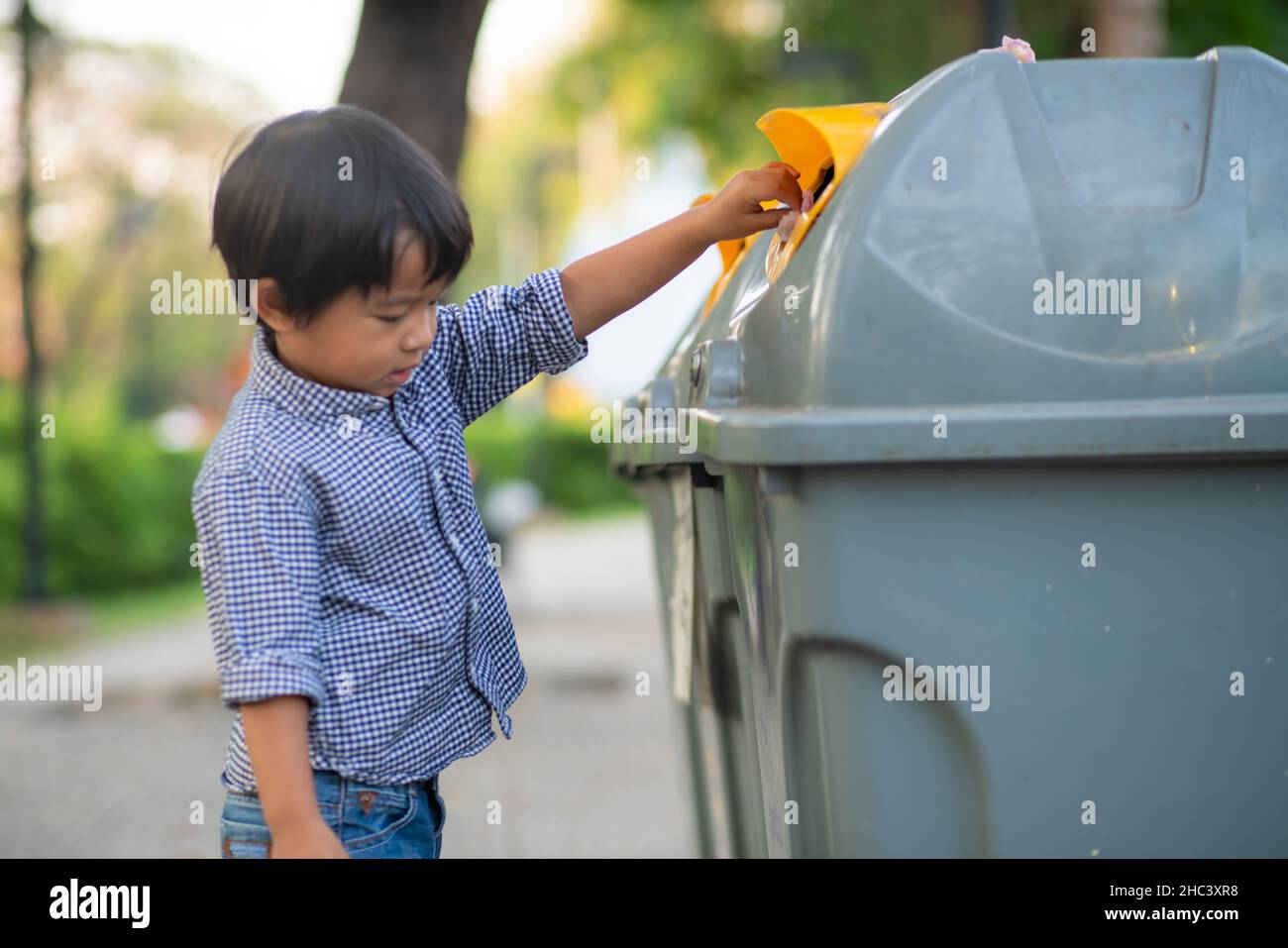 Adorable little boy keep garbage clean to bin in park eco environmennt ...
